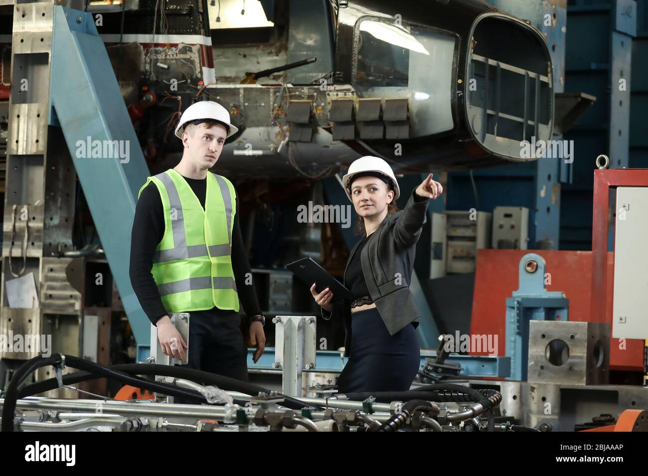 Portrait of a female factory manager in a white hard hat and business ...
