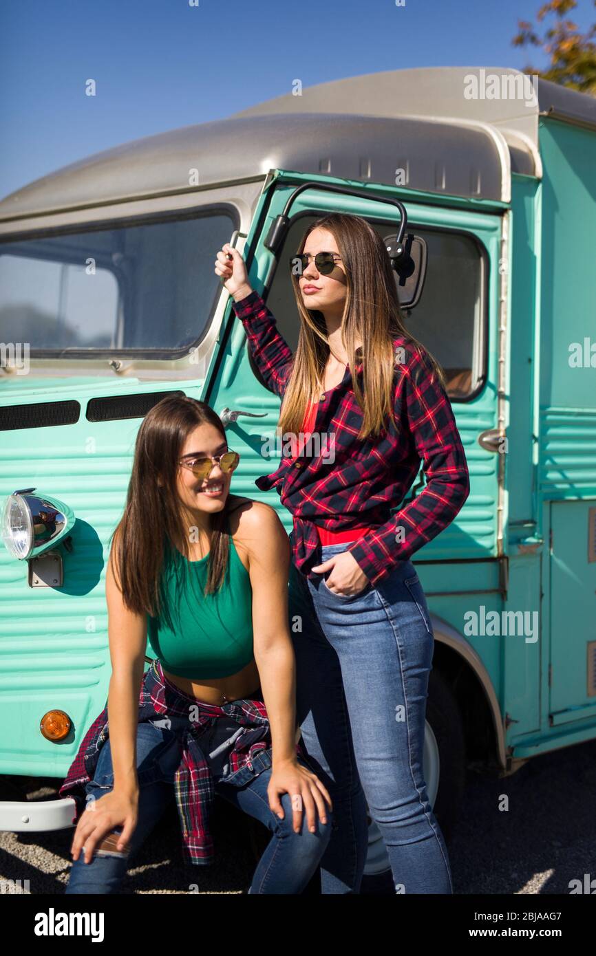 Two smiling pretty young women by the vintage minivan Stock Photo - Alamy