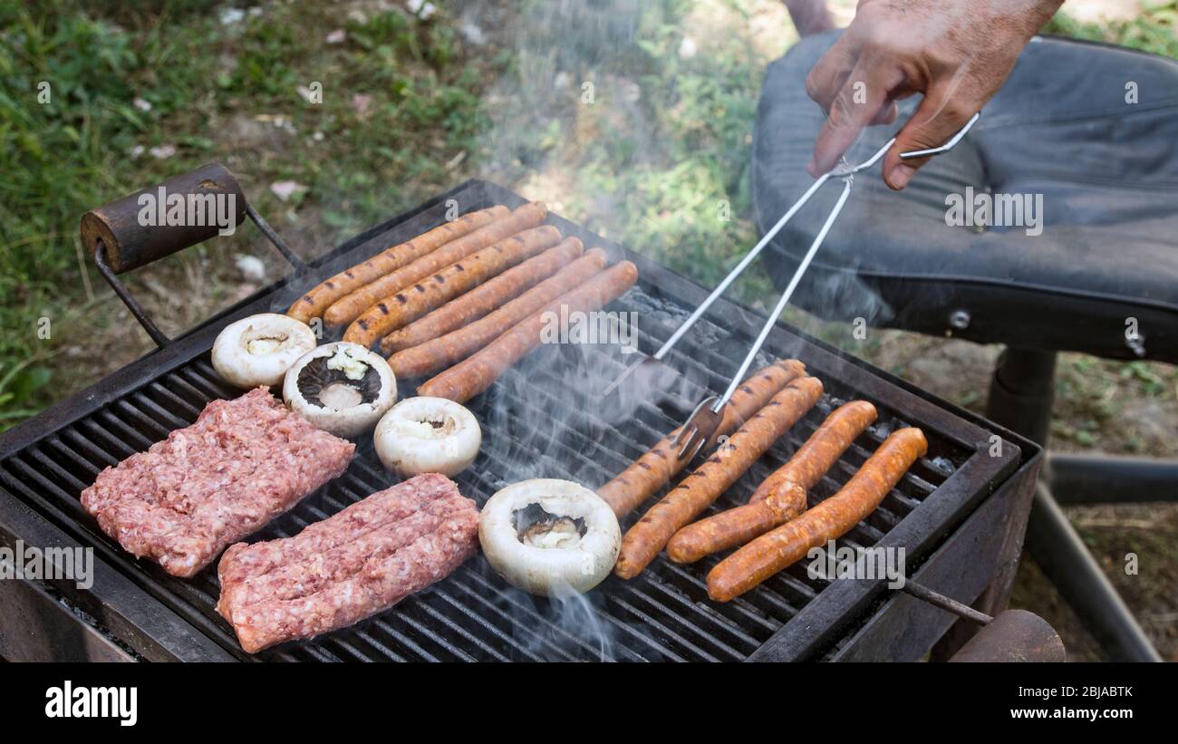 Preparing barbecue meat at picnic in nature. The meat is roasted in a ...