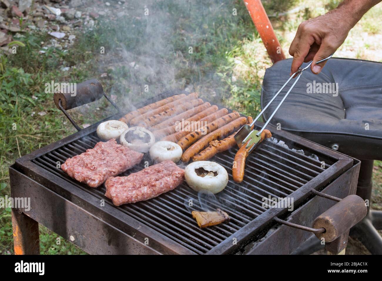 Preparing barbecue meat at picnic in nature. The meat is roasted in a ...