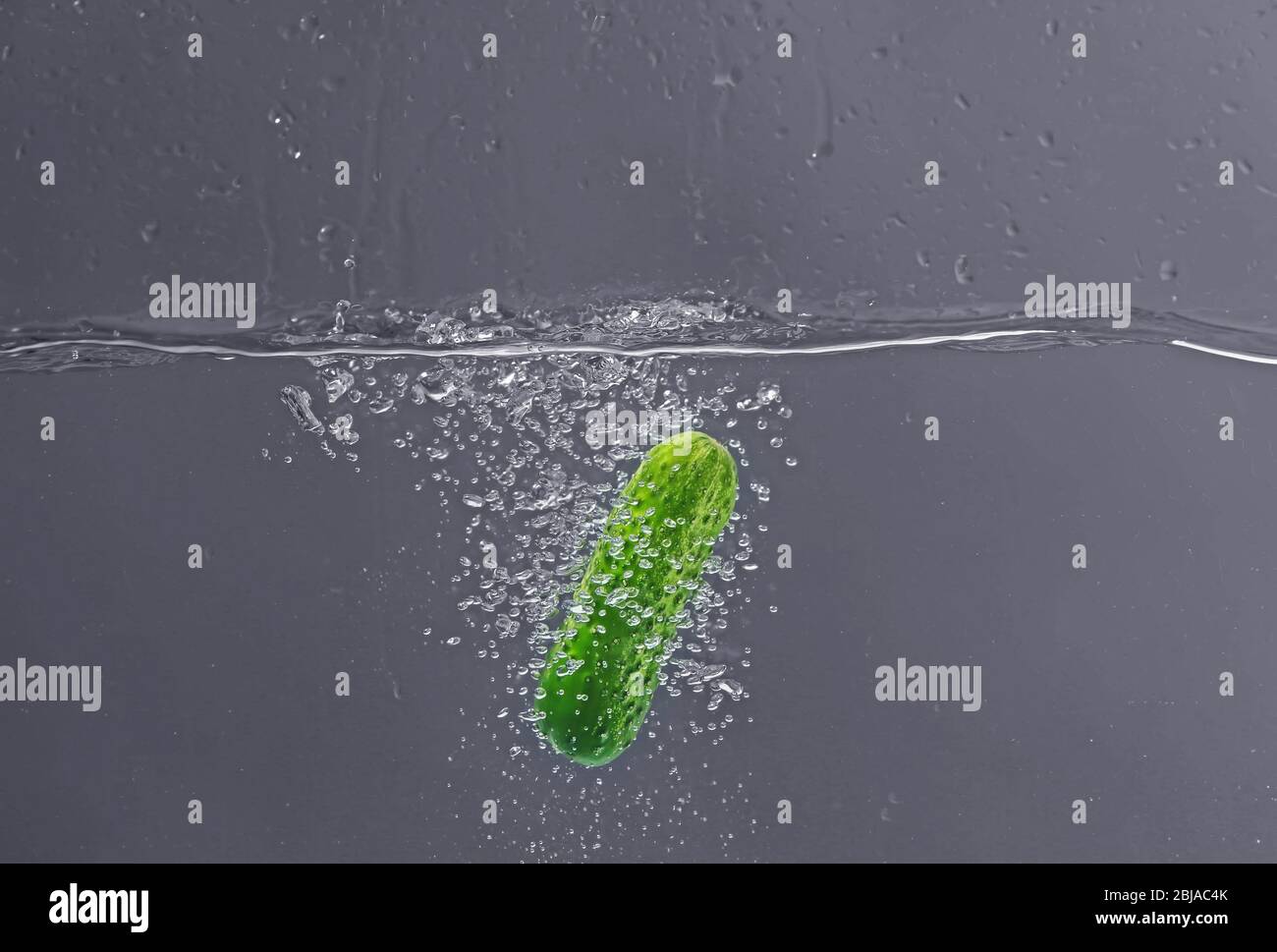 Fresh cucumber falling in water on dark background Stock Photo - Alamy