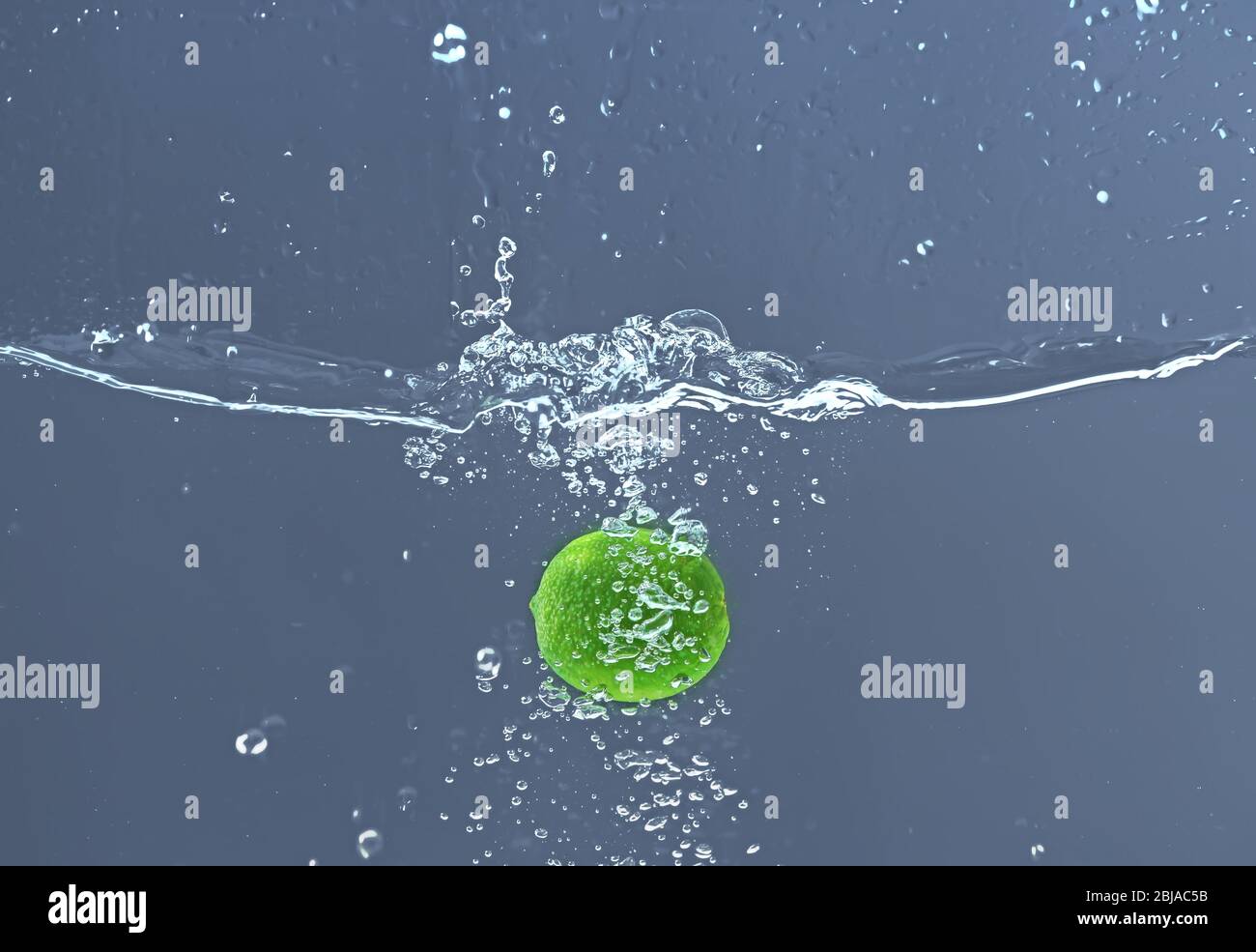 Fresh juicy lime falling in water on dark background Stock Photo - Alamy