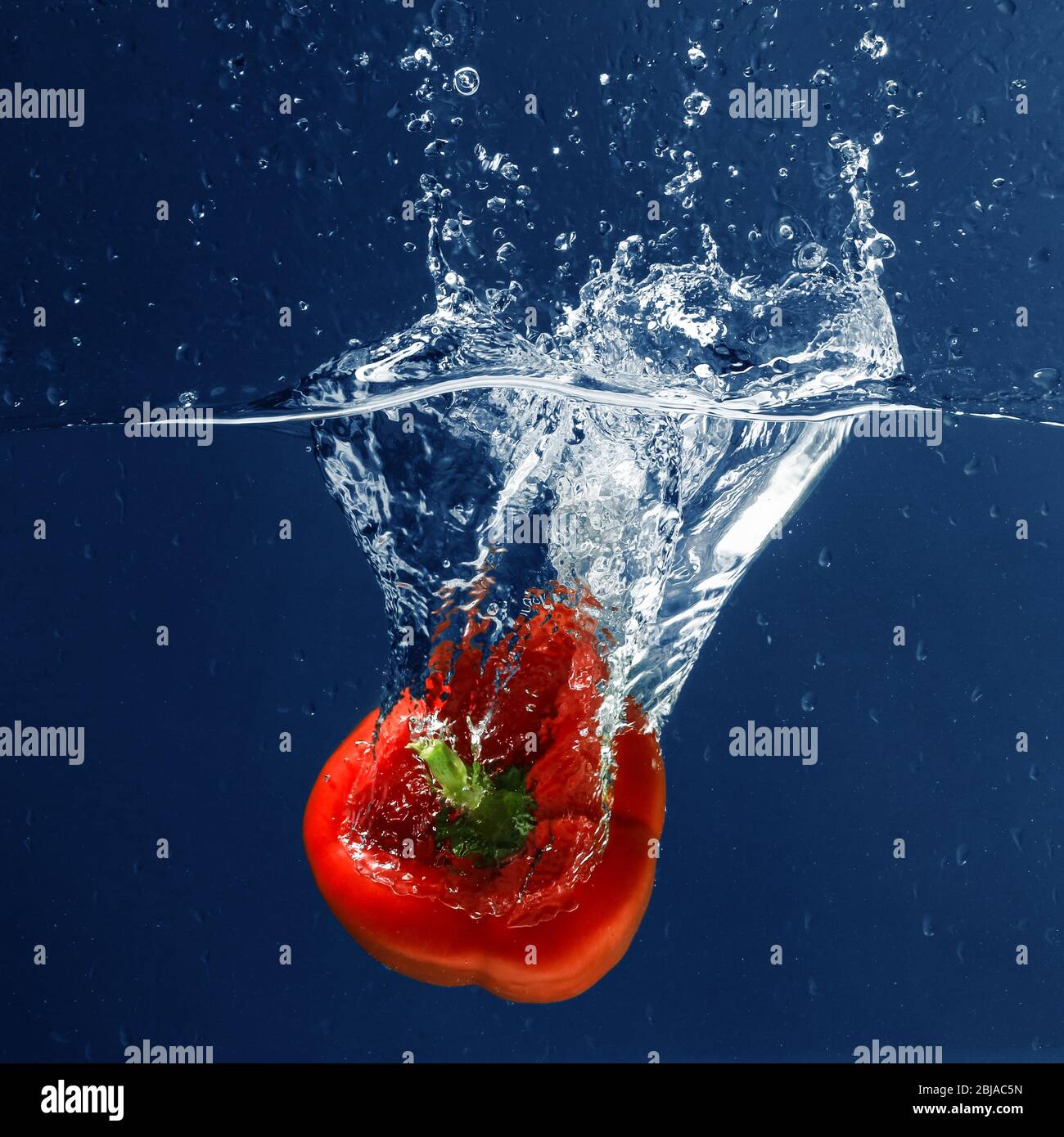 Fresh red bell pepper falling in water on blue background Stock Photo ...