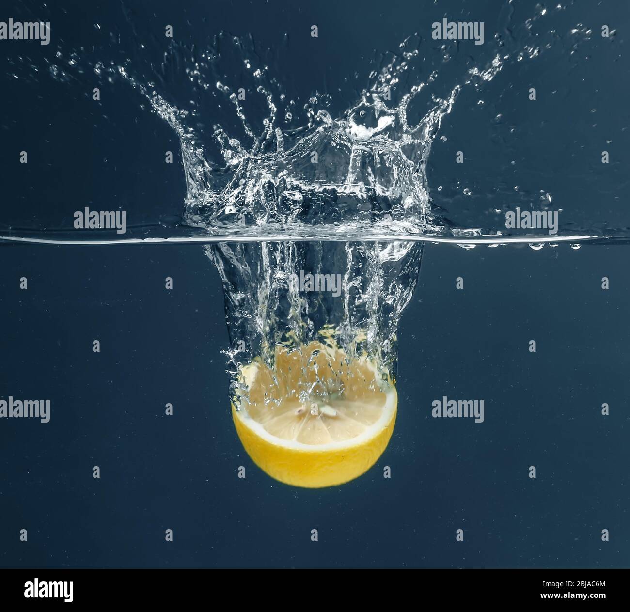 Half of fresh lemon falling in water on dark background Stock Photo - Alamy