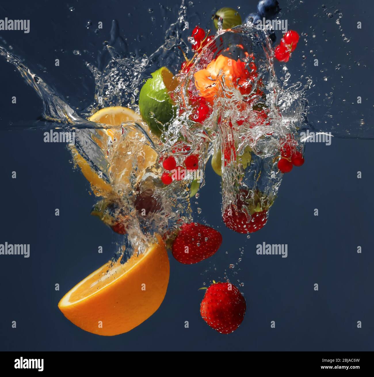 Different fruits and berries falling in water on dark background Stock ...