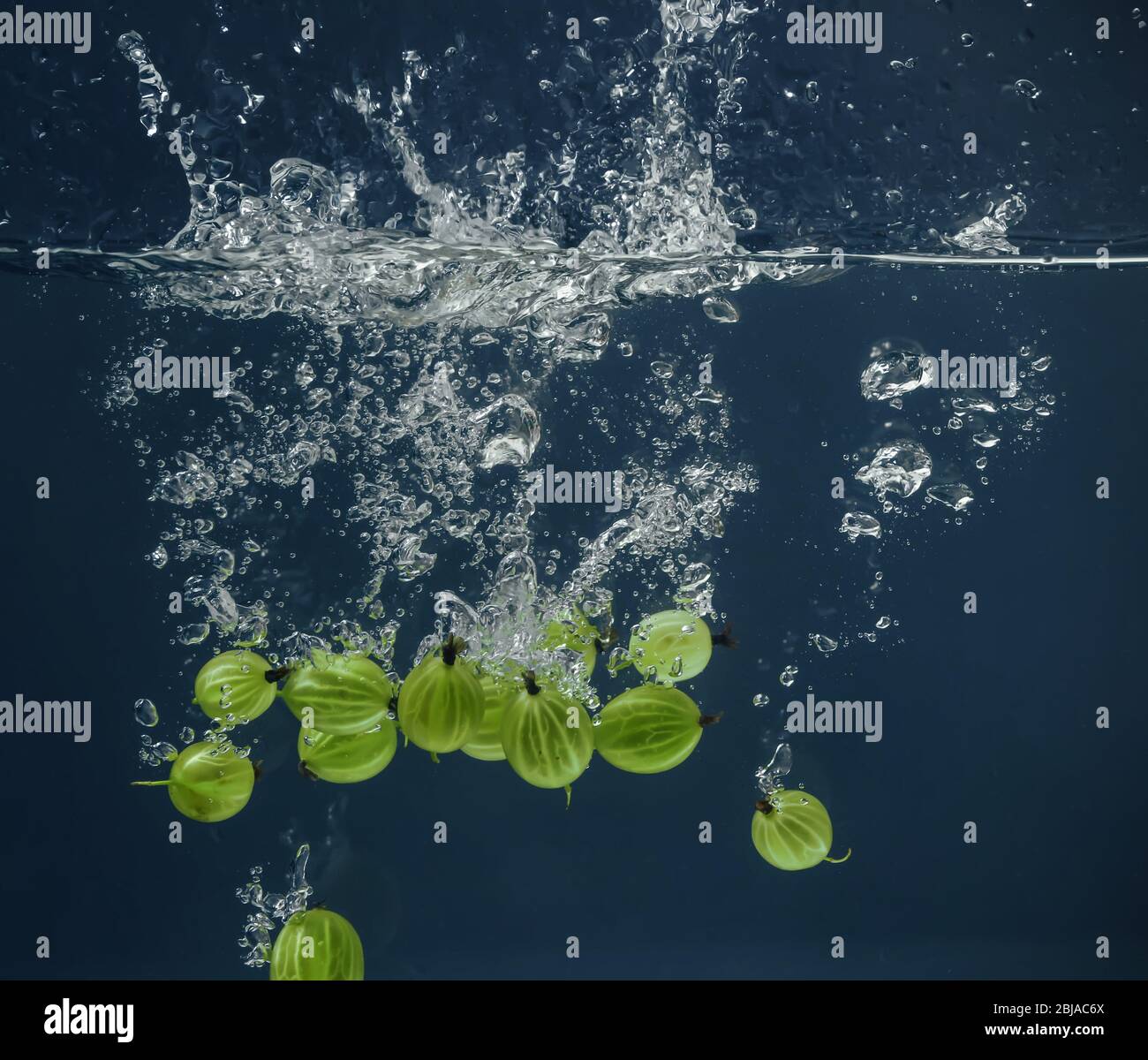 Fresh green gooseberries falling in water on dark background Stock ...