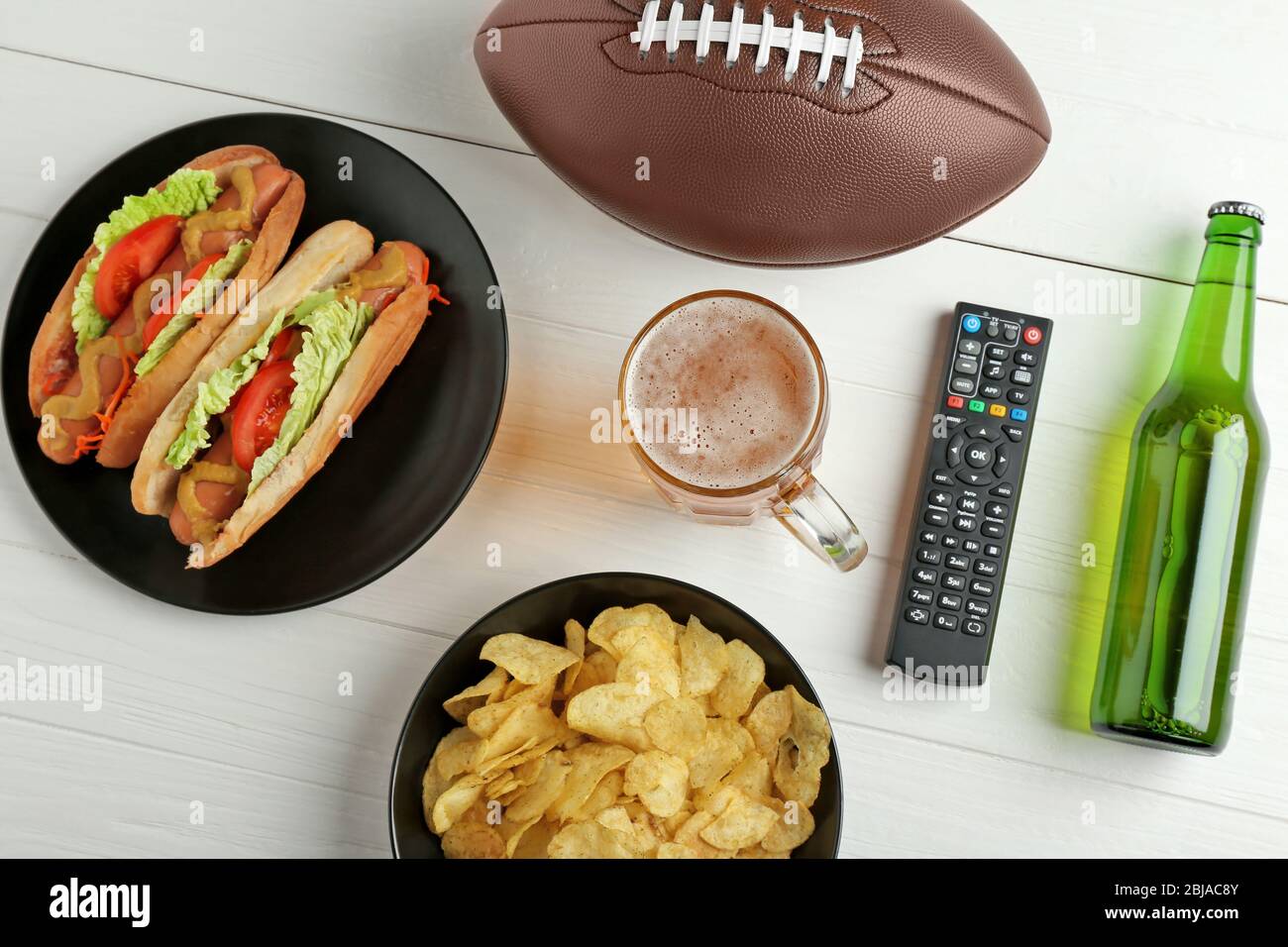 TV remote control with ball, snack and beer on white background Stock ...