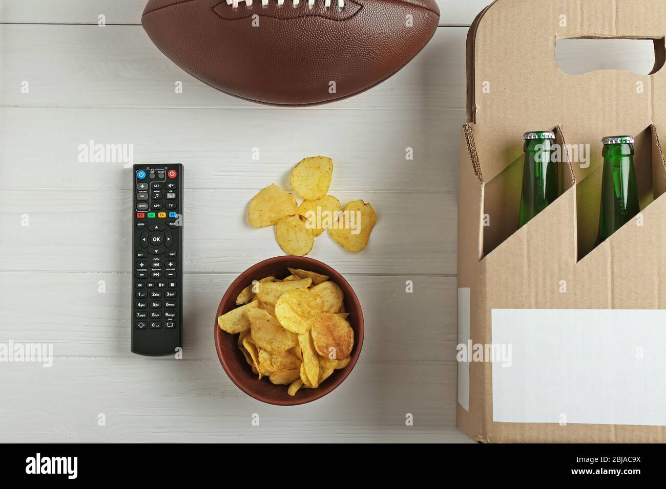 TV remote control with ball, snack and beer on white background Stock ...
