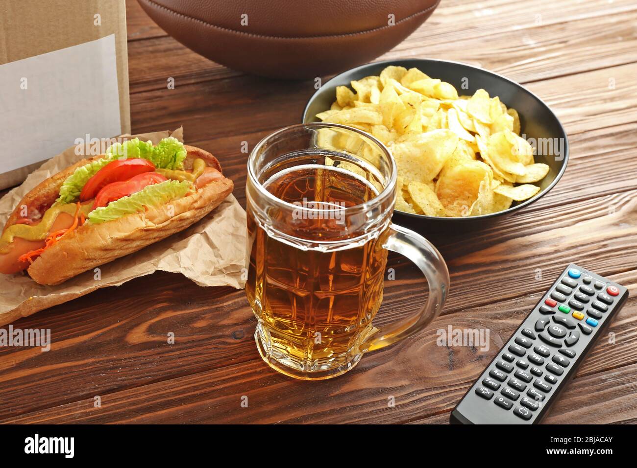 Glass of beer, snack and TV remote control on wooden background Stock ...
