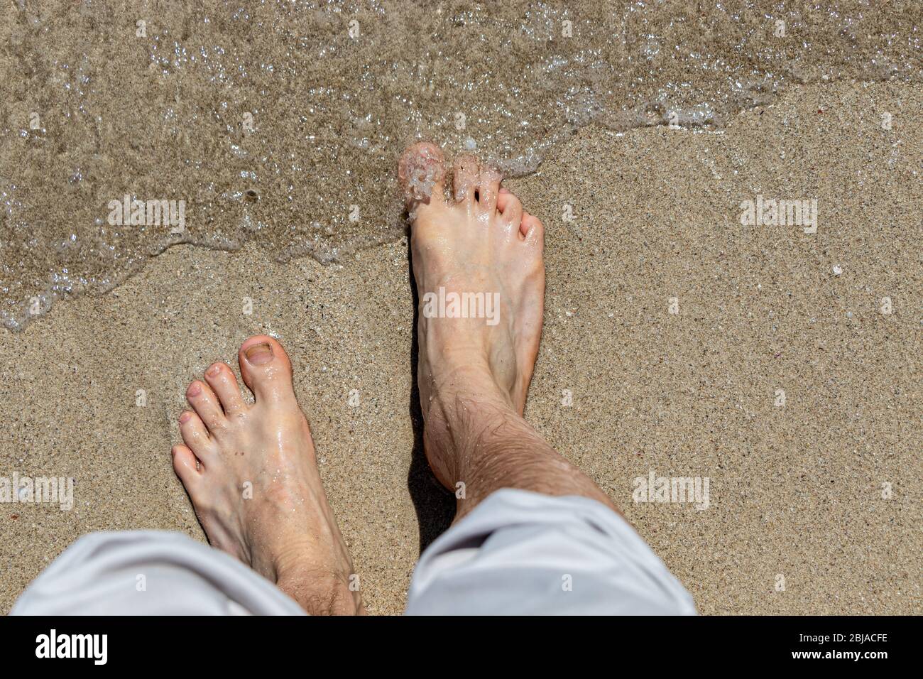top down view of feet waiting for a wave to come in, oh the ...