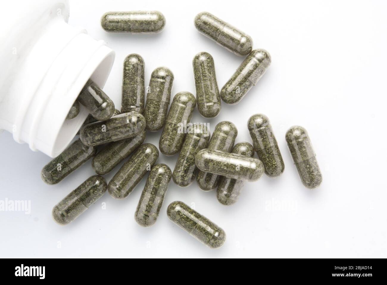 herb capsule from bottle on white background Stock Photo - Alamy