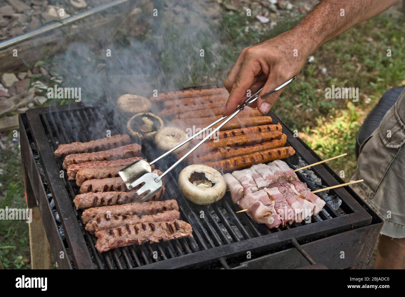 Preparing barbecue meat at picnic in nature. The meat is roasted in a ...