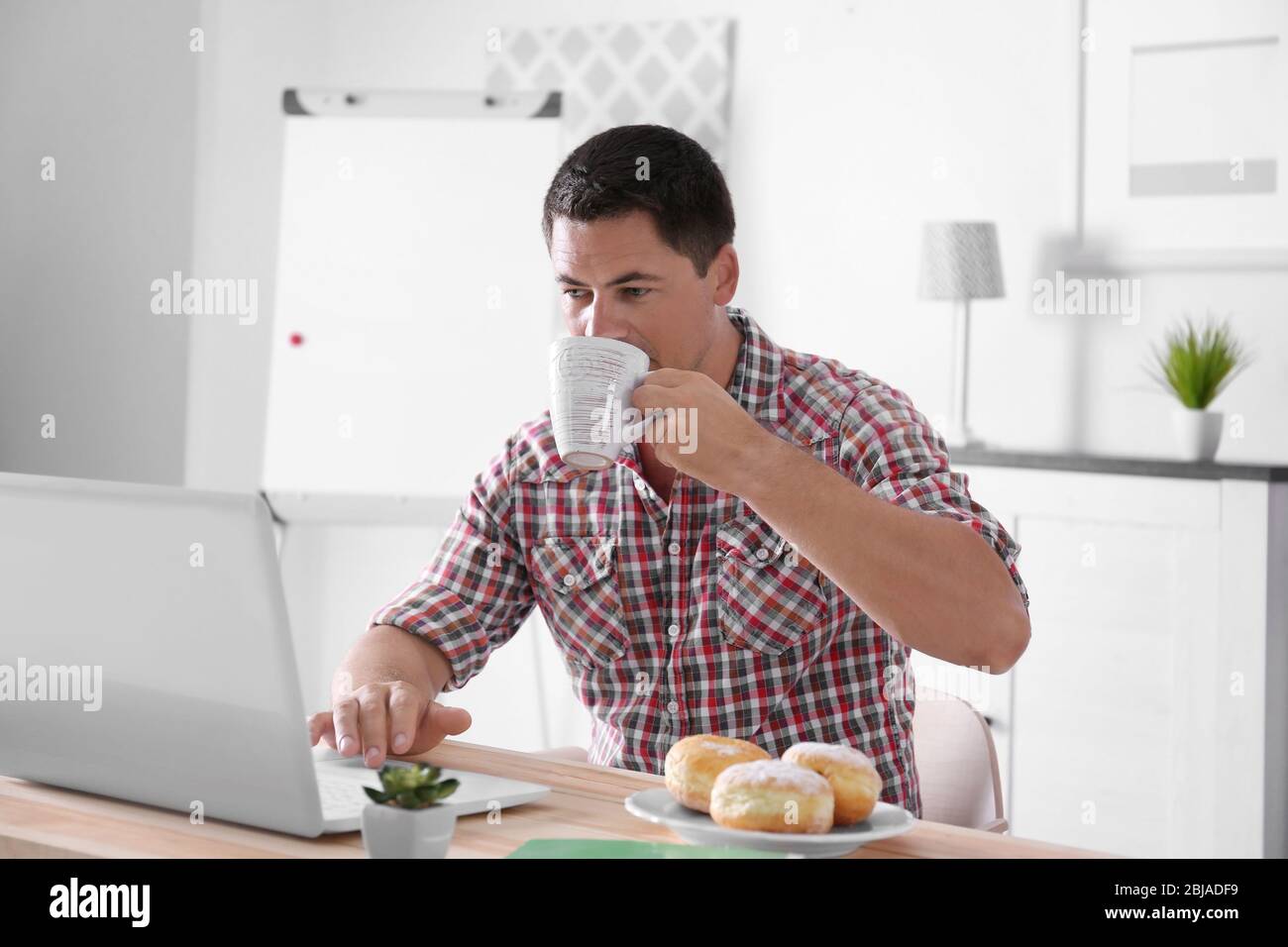 Handsome man eating in front of laptop Stock Photo - Alamy