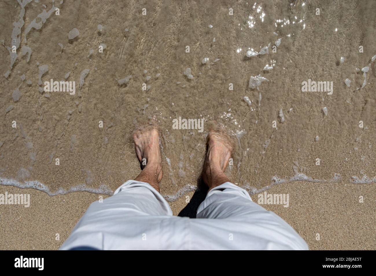 top down view of feet waiting for a wave to come in, oh the ...