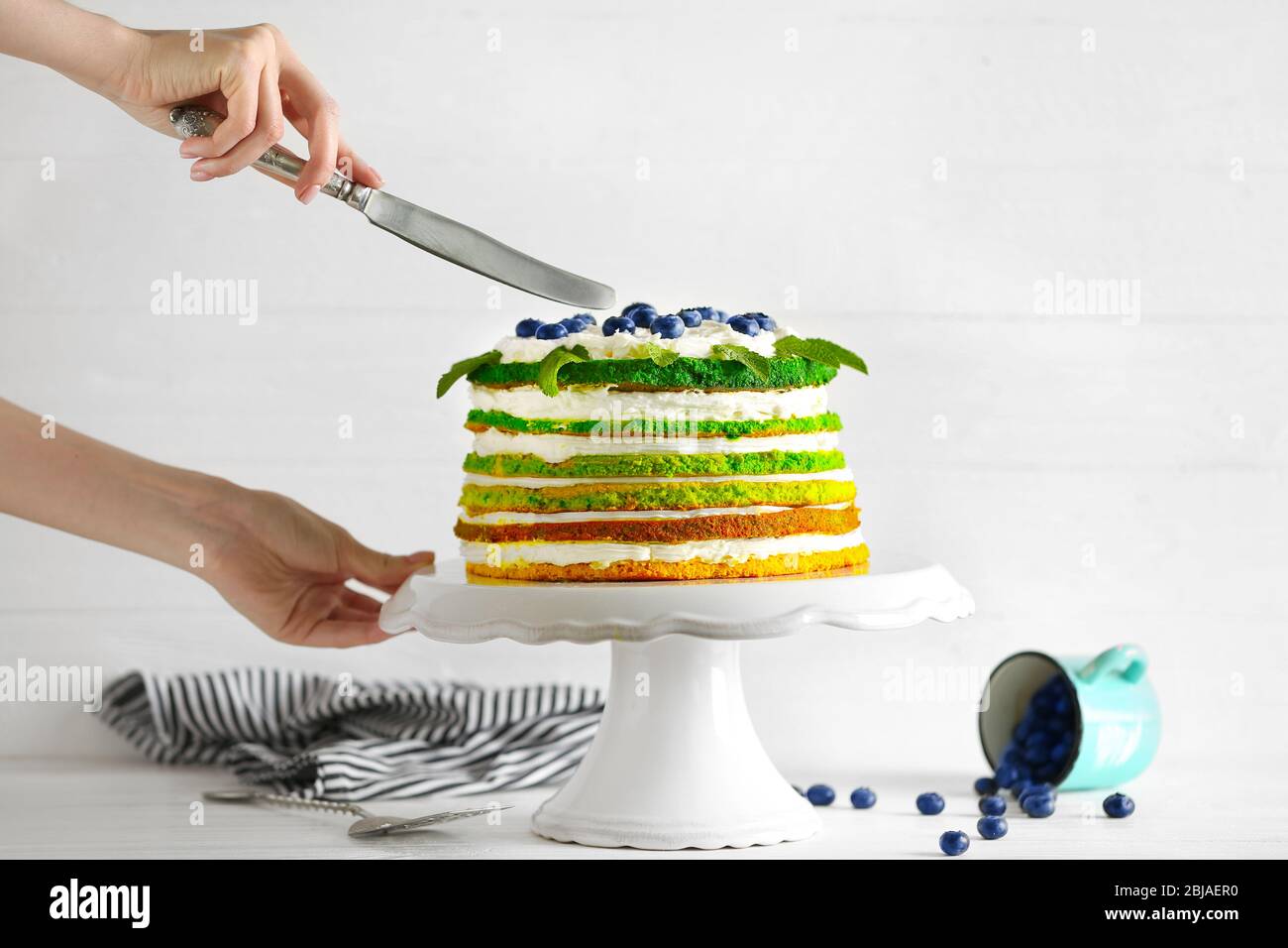Woman cutting delicious cake on light background Stock Photo - Alamy