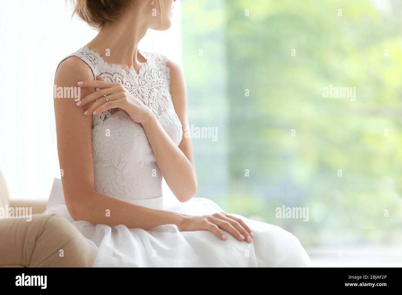 Bride in beautiful wedding gown sitting on sofa Stock Photo - Alamy