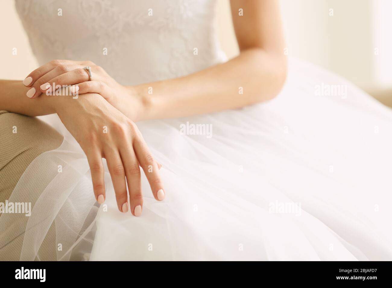 Bride in beautiful wedding gown sitting on sofa Stock Photo - Alamy