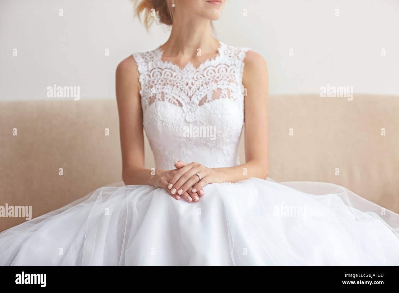 Bride in beautiful wedding gown sitting on sofa Stock Photo - Alamy