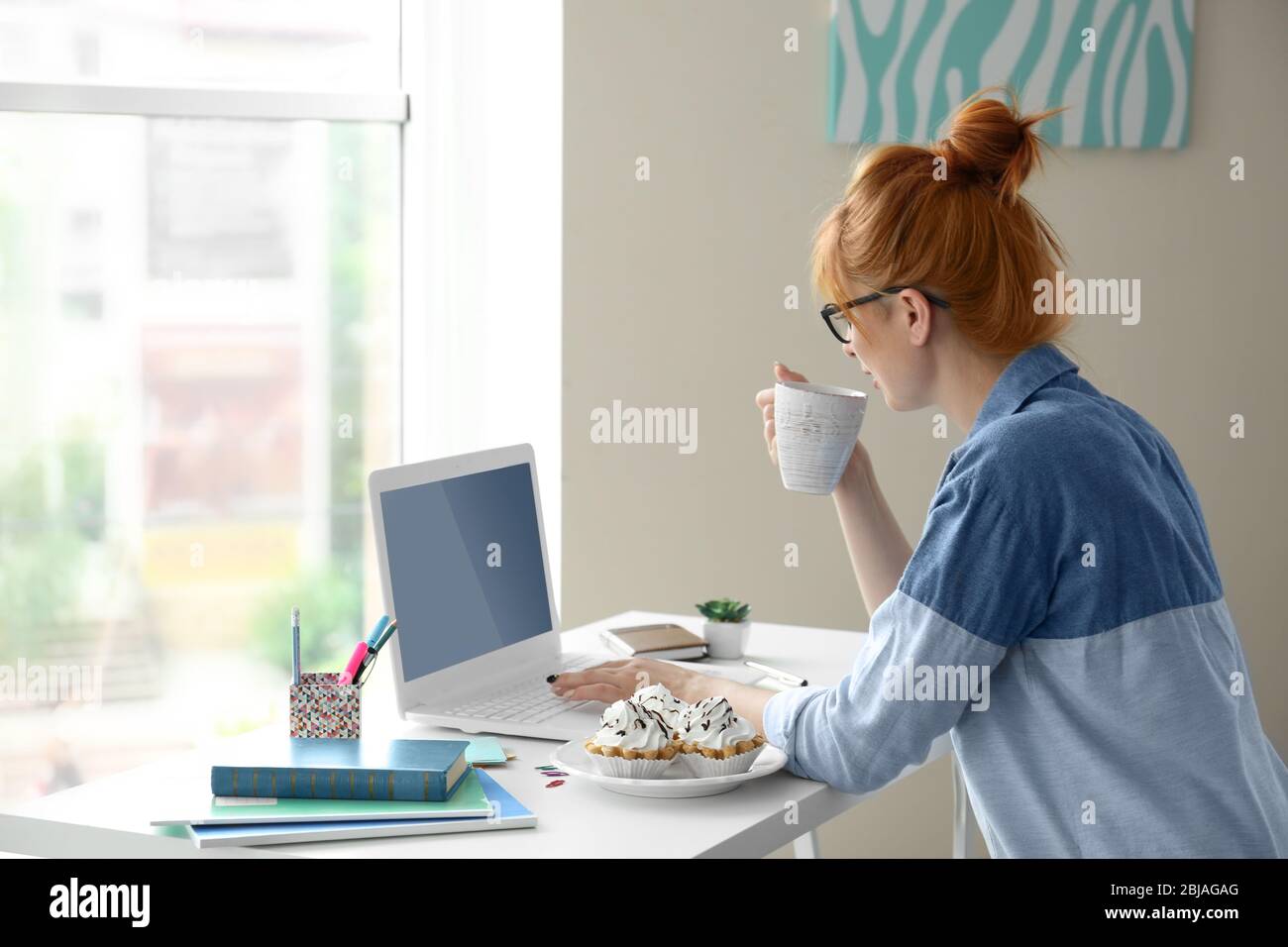 Beautiful girl eating in front of computer Stock Photo - Alamy