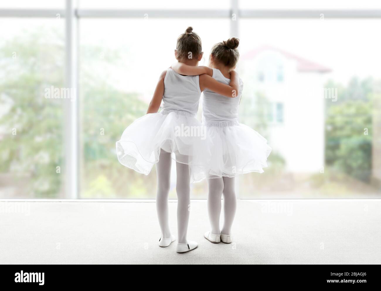 Cute girls looking out window in ballet class Stock Photo - Alamy