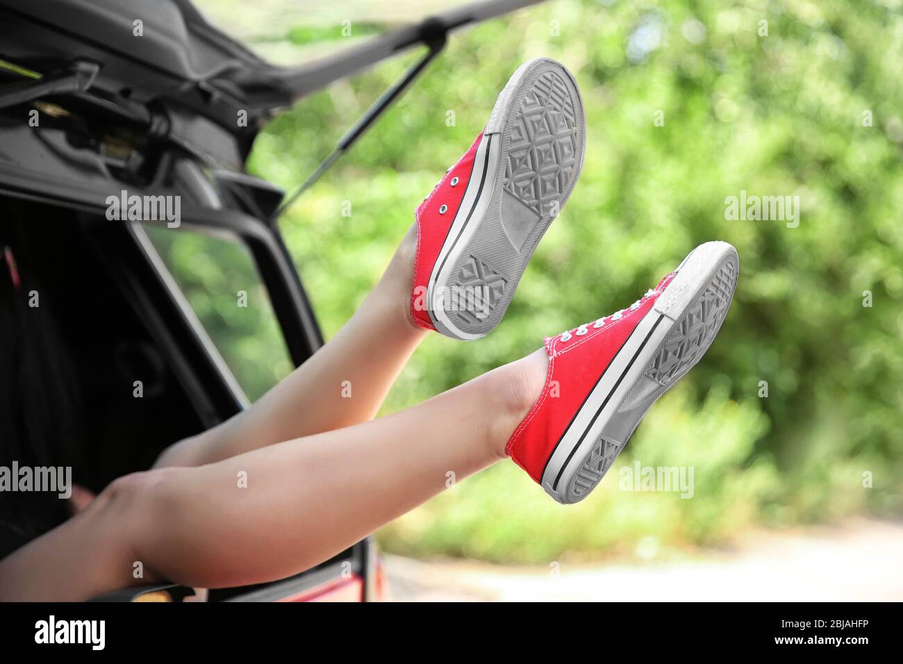 Female legs with red shoes through car window Stock Photo - Alamy