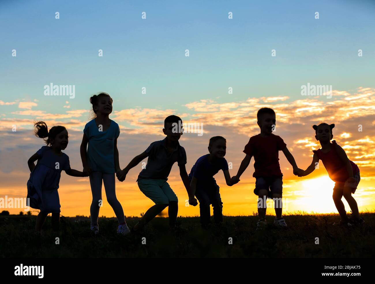 Happy kids silhouettes on sunset background Stock Photo - Alamy