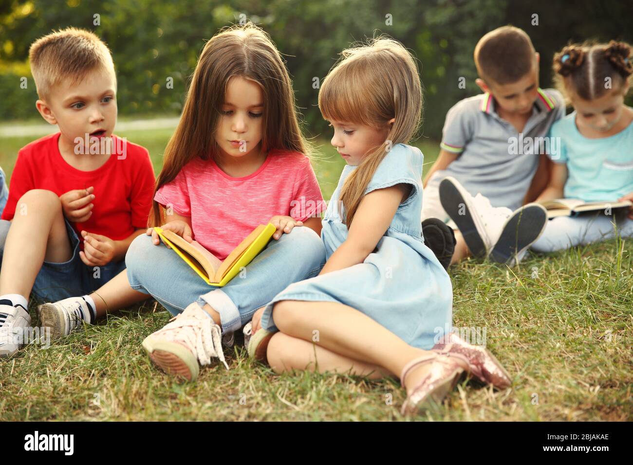 Group of happy kids reading books in park Stock Photo - Alamy