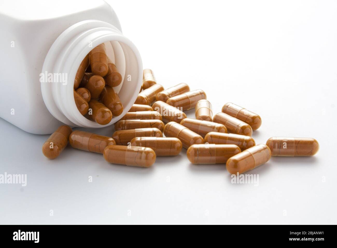 herb capsule from bottle on white background Stock Photo - Alamy