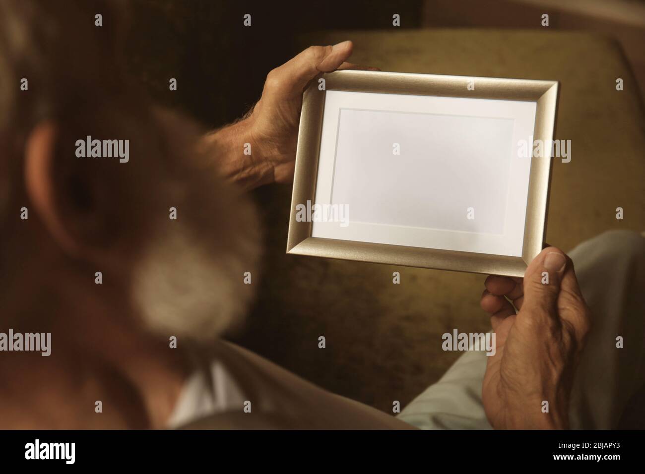 Old man holding and looking at photo frame Stock Photo - Alamy