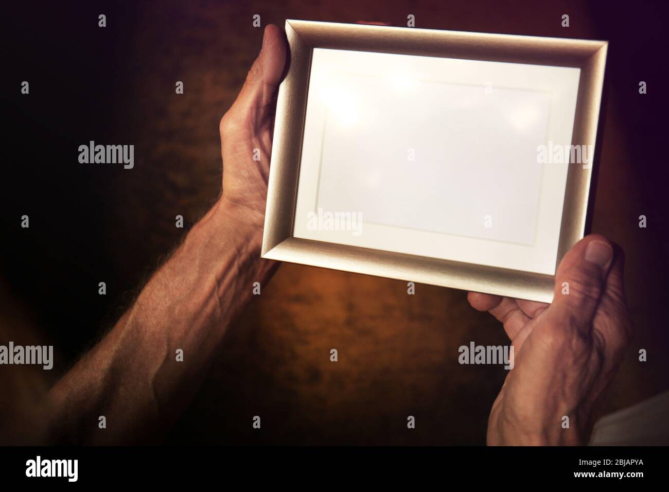 Old man holding and looking at photo frame Stock Photo - Alamy