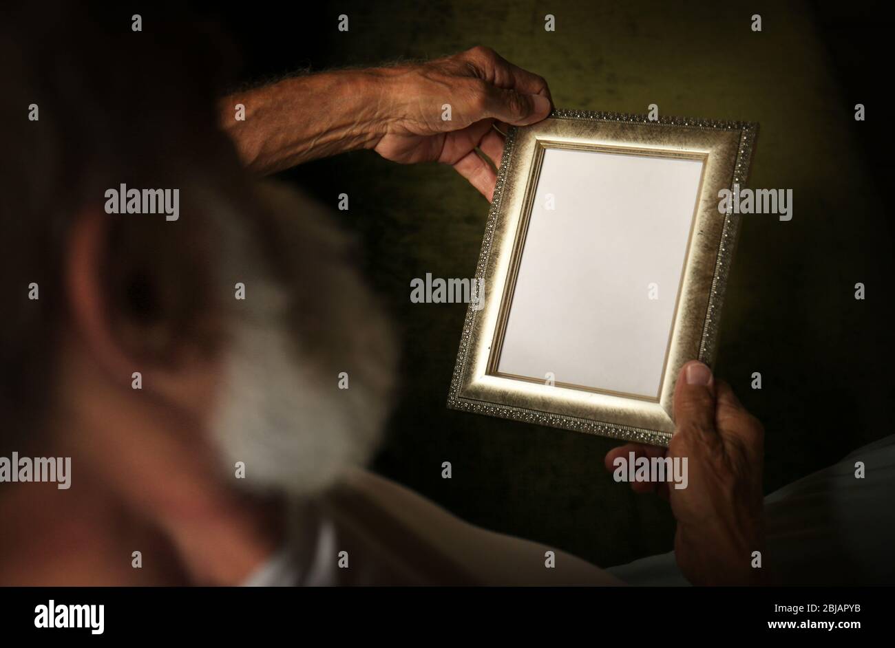 Old man holding and looking at photo frame Stock Photo - Alamy