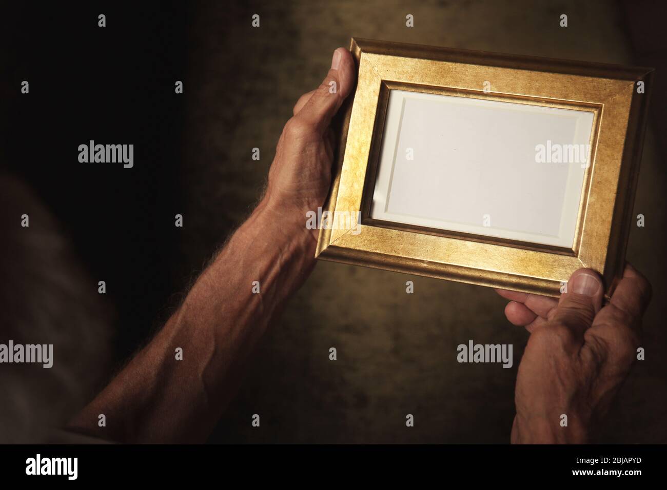 Old man holding and looking at photo frame Stock Photo - Alamy