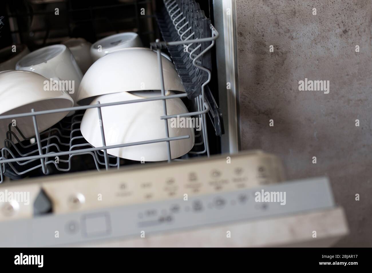 Large white bowls in the compartment of an open dishwasher. Cleaning ...