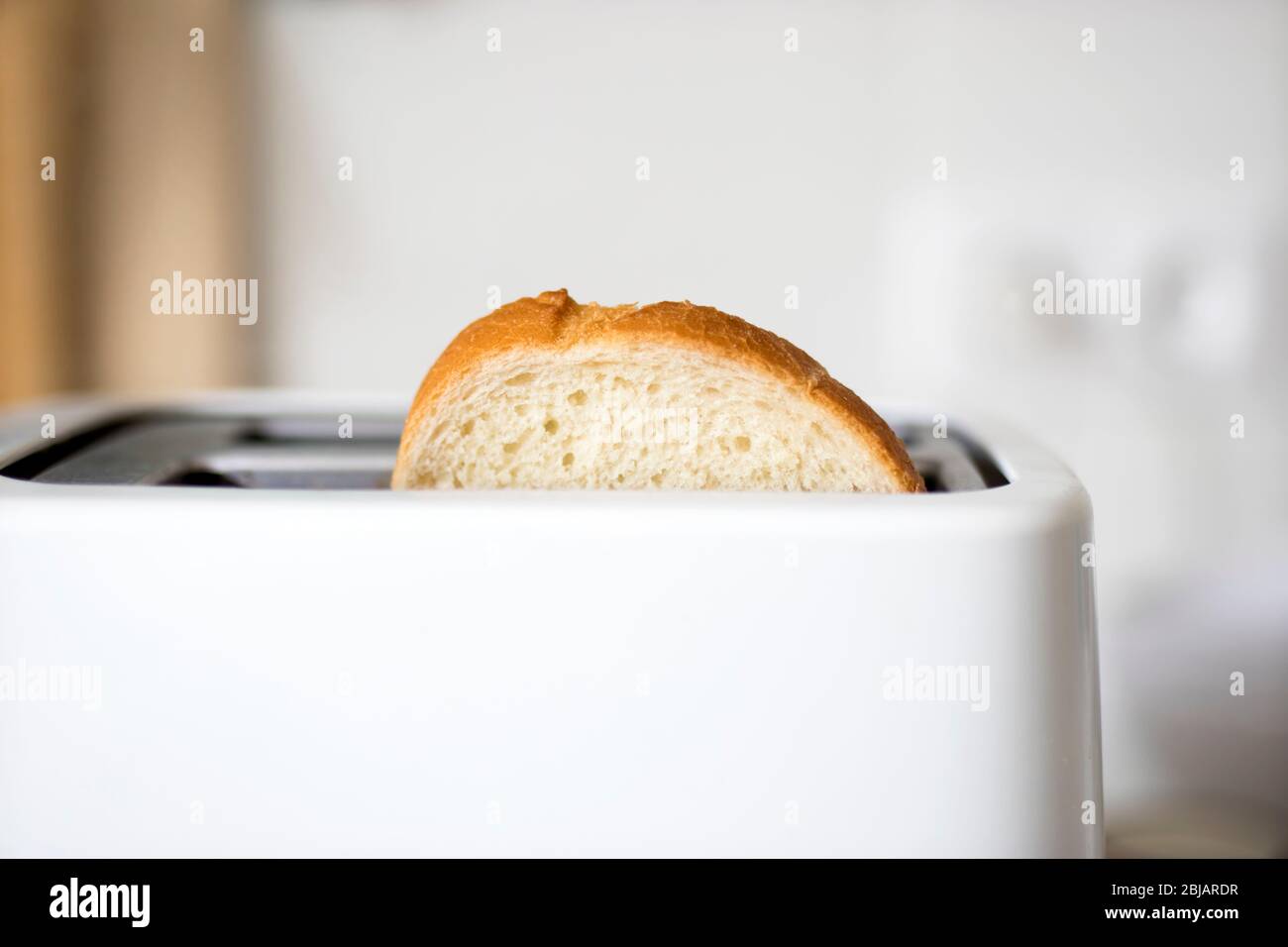A piece of bread in a toaster on the background of a white ceramic ...