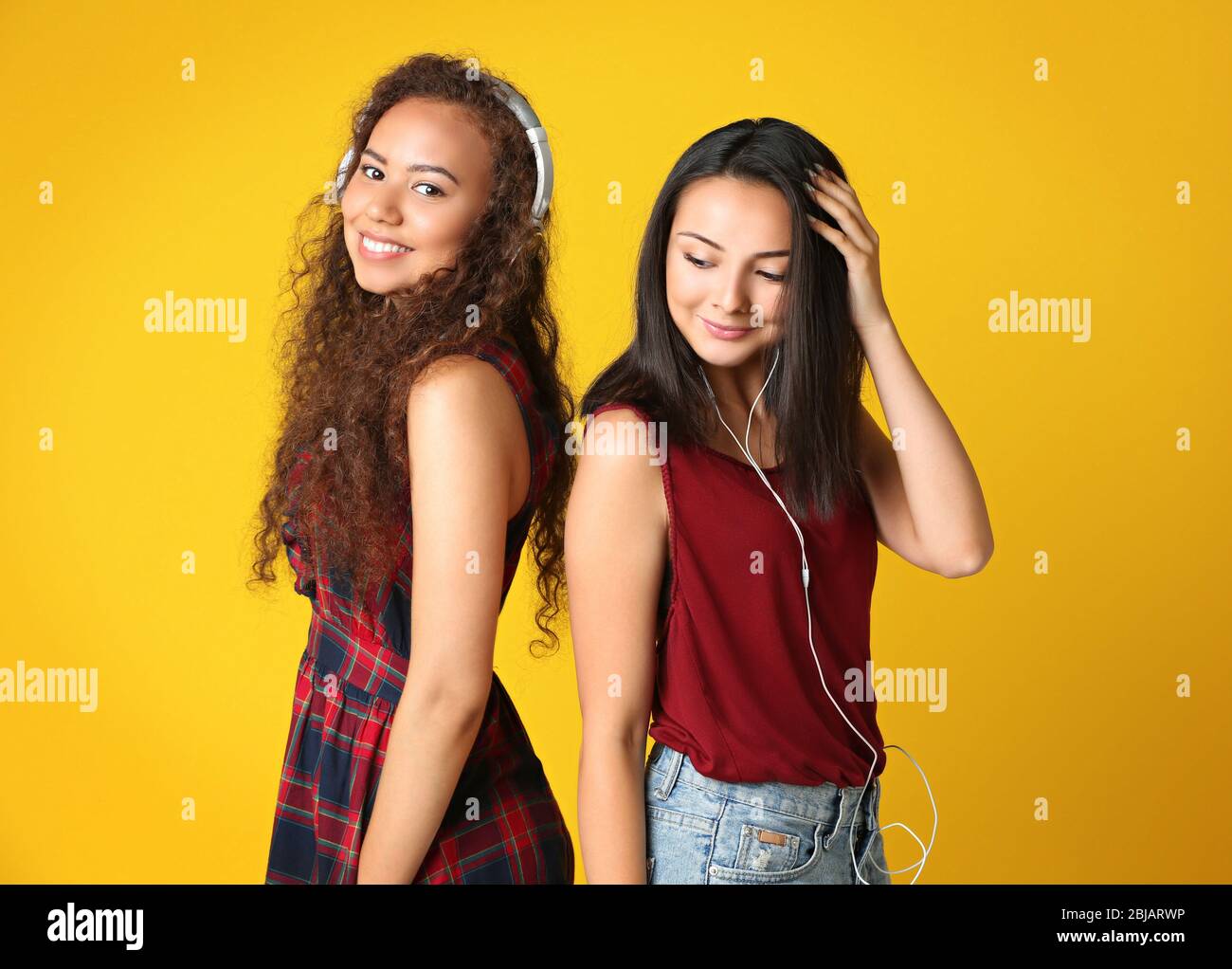 Beautiful girls listening music on yellow background Stock Photo - Alamy