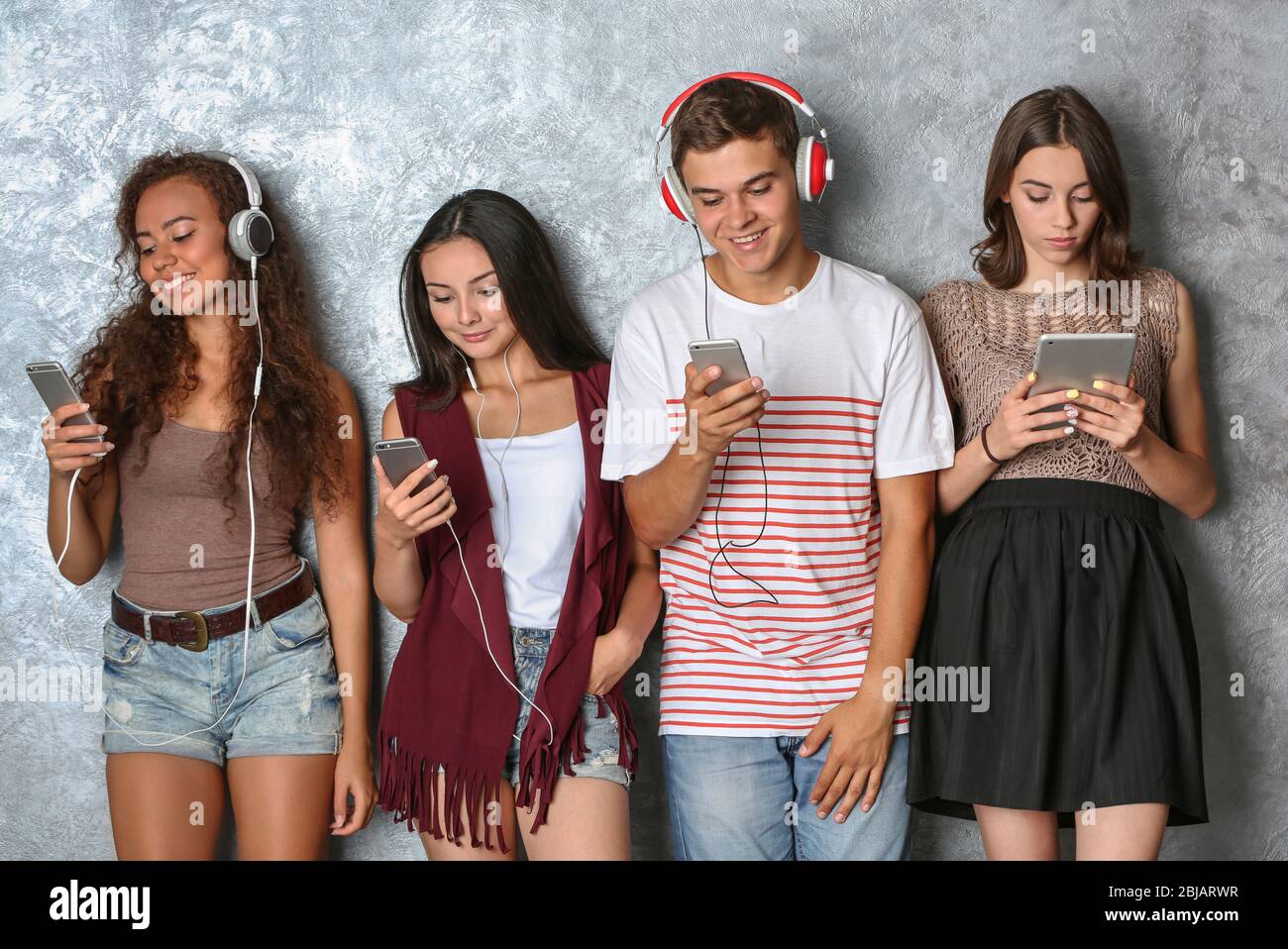 Happy friends with gadgets on grey background Stock Photo - Alamy