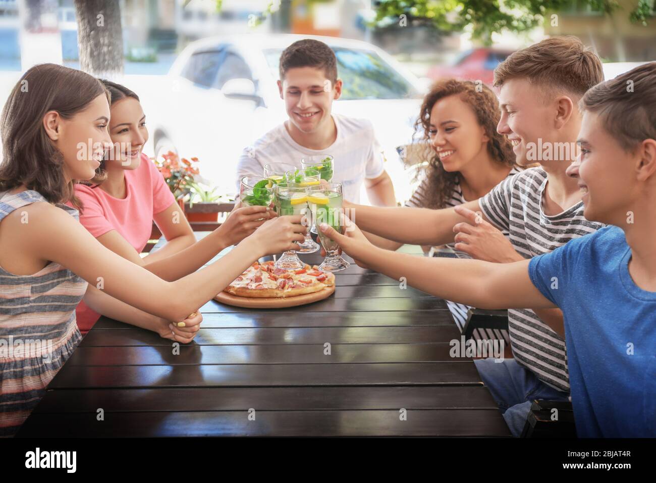 Happy friends eating pizza in cafe Stock Photo - Alamy