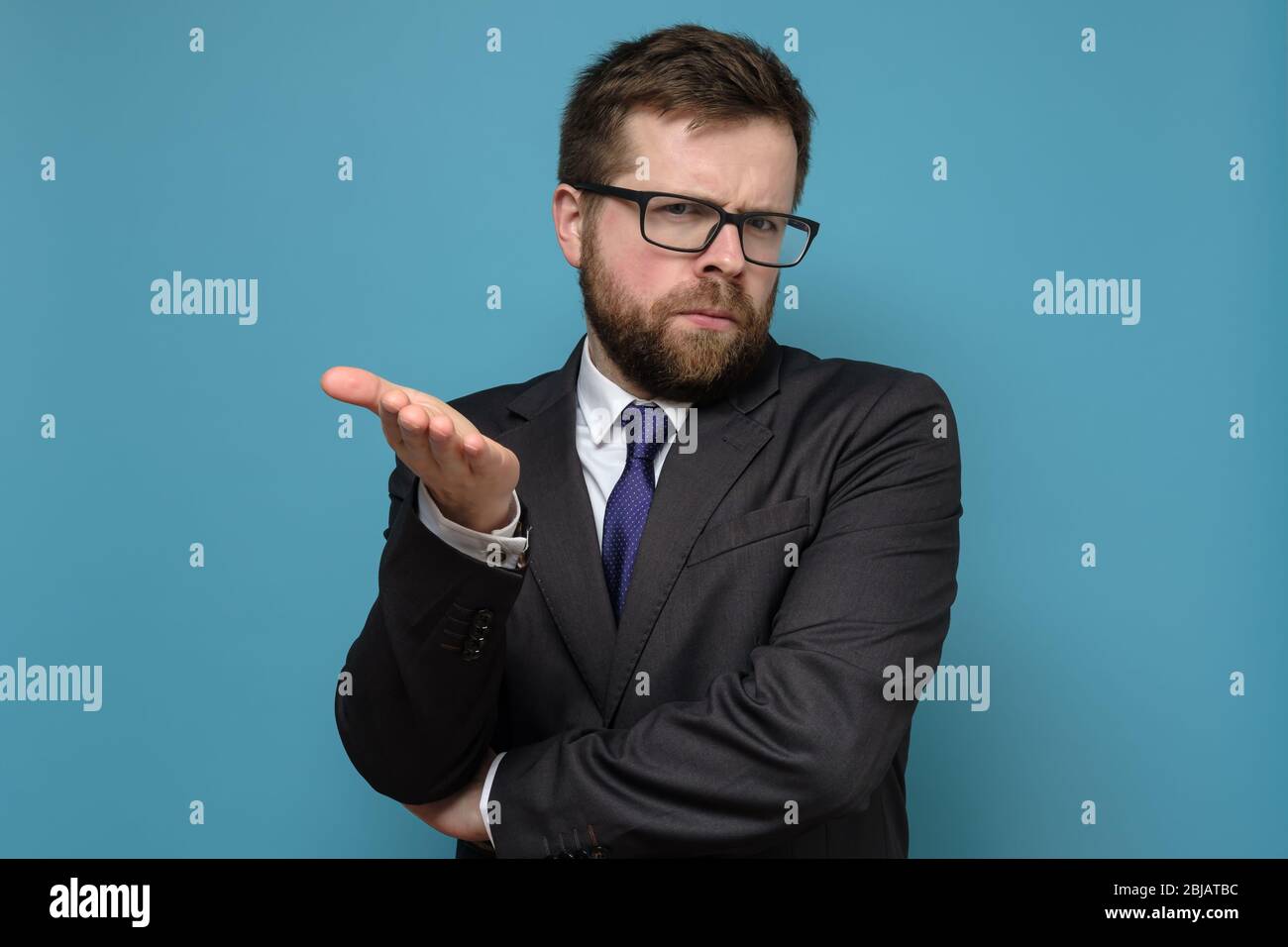 Business man in a suit is bewildered, he strictly looks at the camera ...