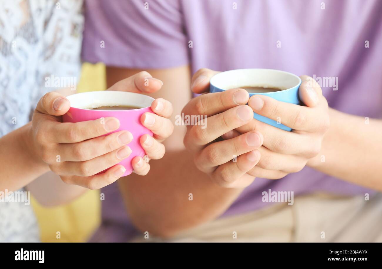 Couple holding cups of coffee together Stock Photo - Alamy