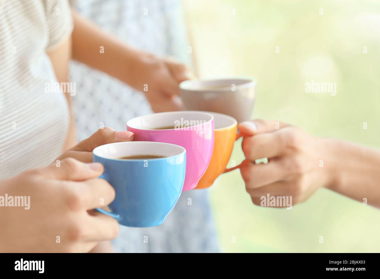 Group of people holding cups of coffee together Stock Photo - Alamy