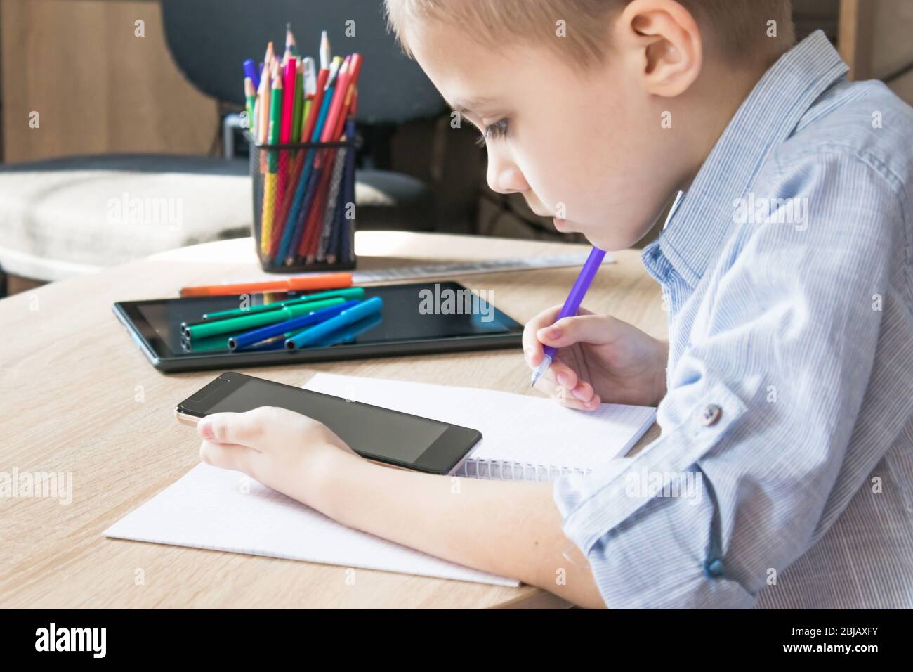 A child is learning distance learning lessons on a mobile phone. The ...