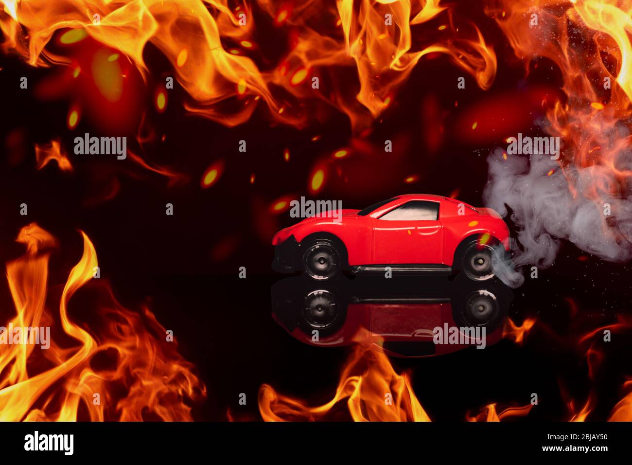 Red Toy car escaping an explosion of fire and flames on a black shiny ...
