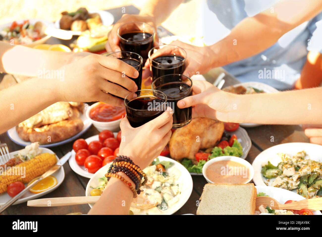 Friends cheering with drinks on picnic Stock Photo - Alamy