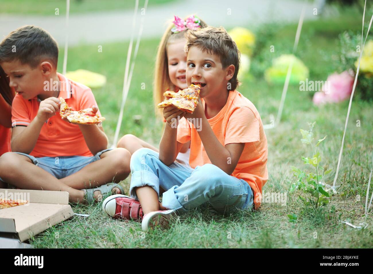 Children eating pizza on grass Stock Photo - Alamy