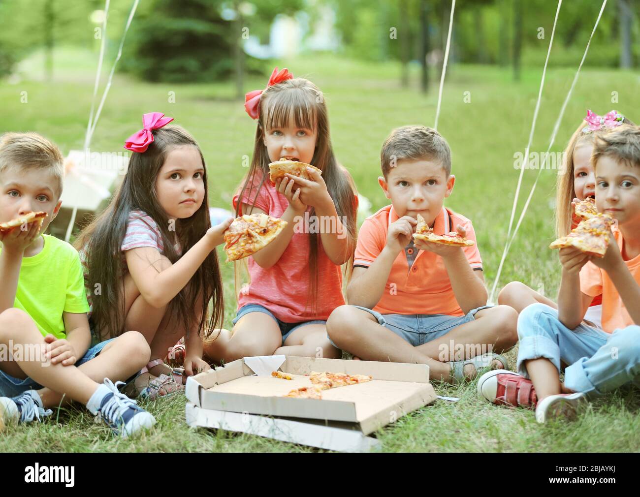 Children eating pizza on grass Stock Photo - Alamy