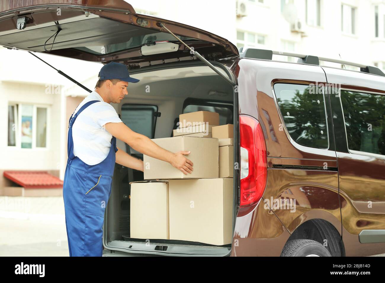 Delivery concept. Postman getting parcels from a car Stock Photo - Alamy
