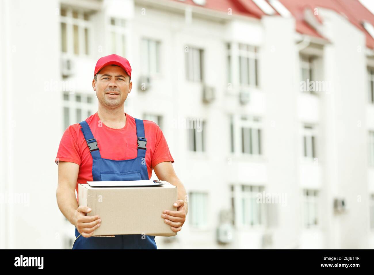 Delivery concept. Postman with parcel on building background Stock ...