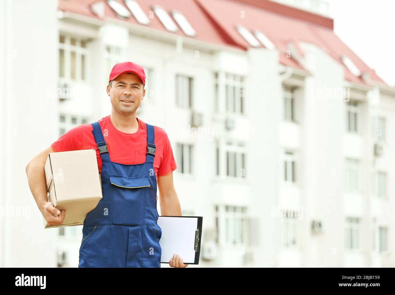 Delivery concept. Postman with parcel on building background Stock ...