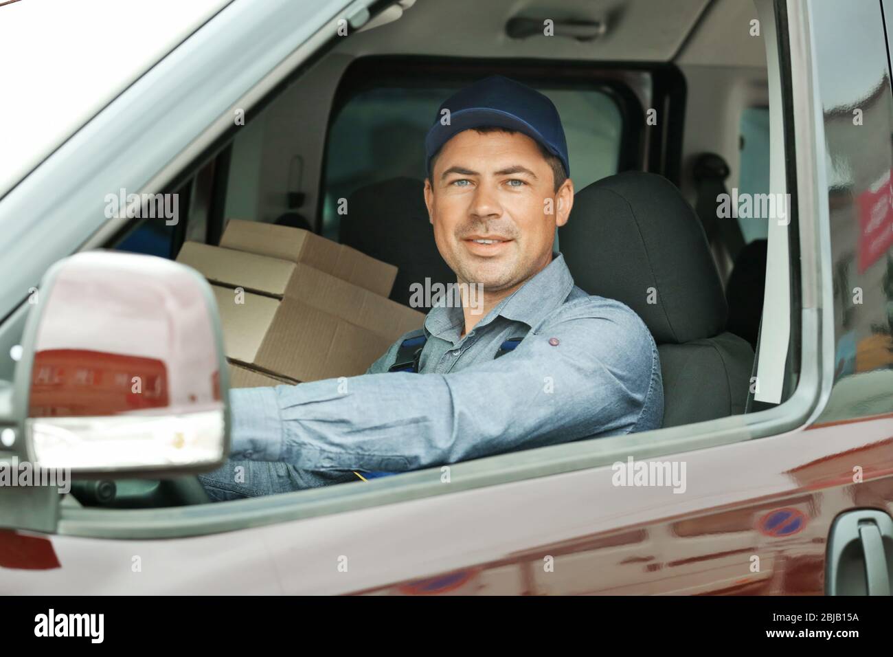 Delivery concept. Postman driving delivery car Stock Photo - Alamy