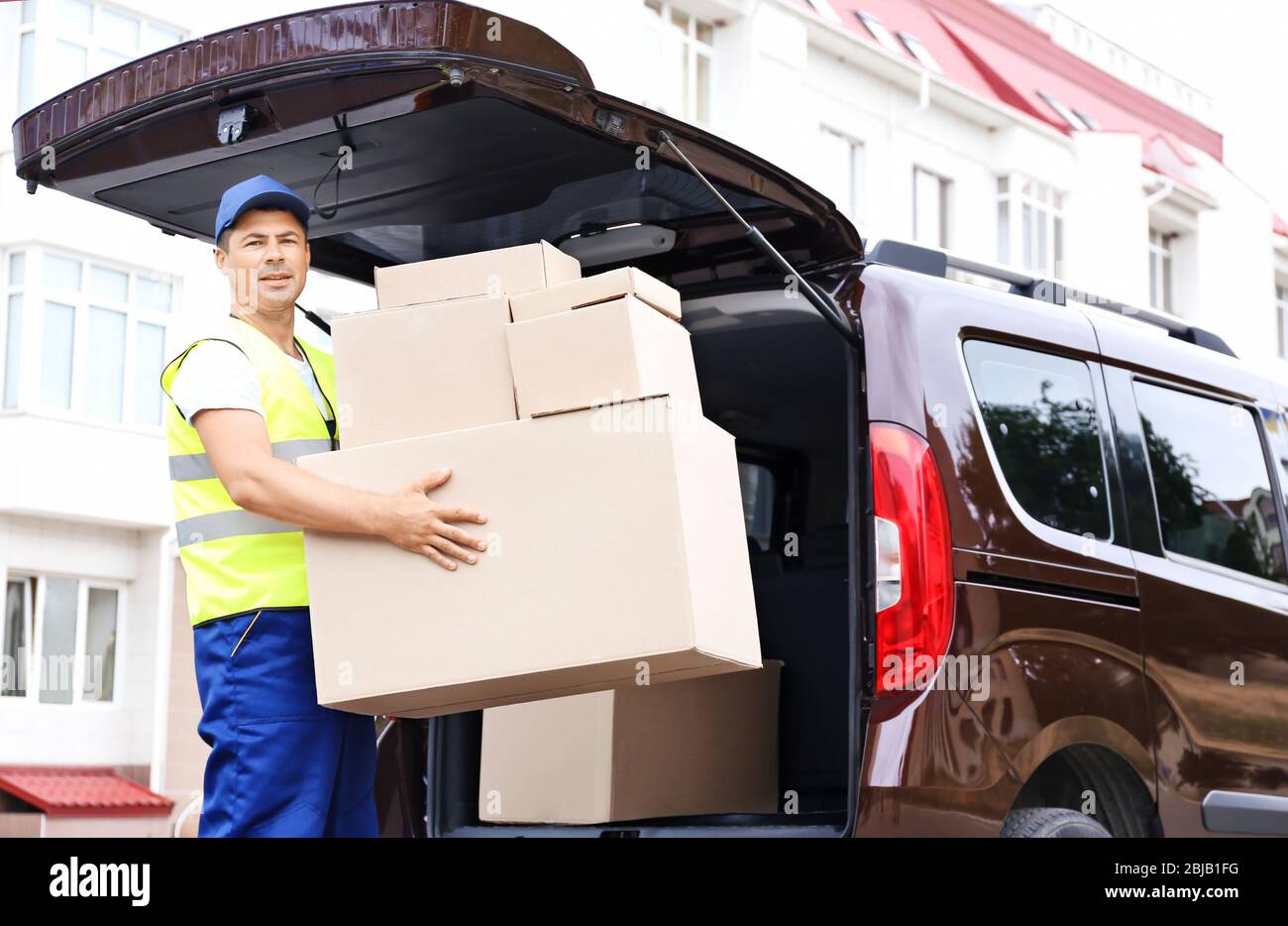 Delivery concept. Postman getting parcels from a car Stock Photo - Alamy